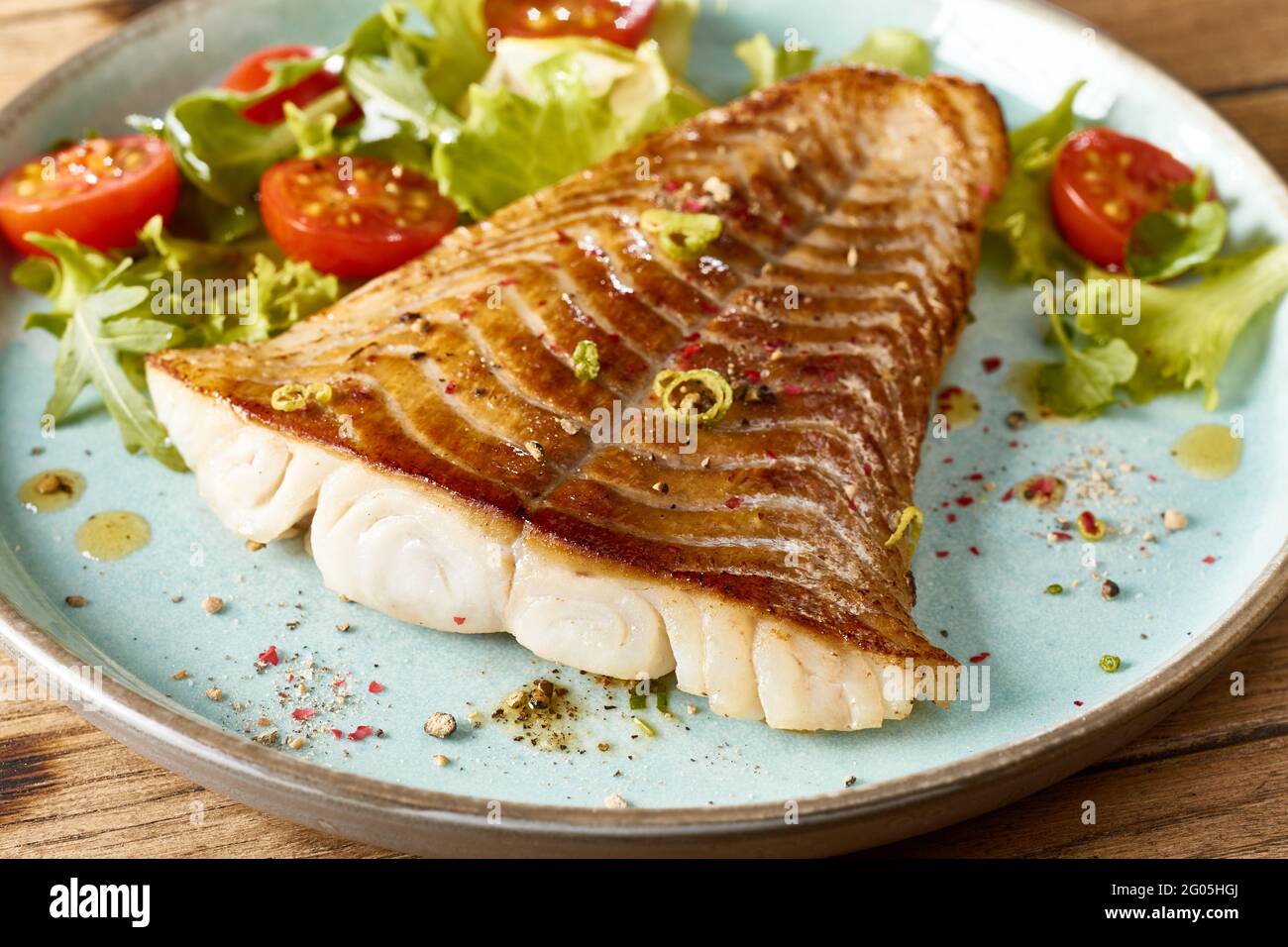 High angle of tasty roast pollock fillet with cut cherry tomatoes and ...