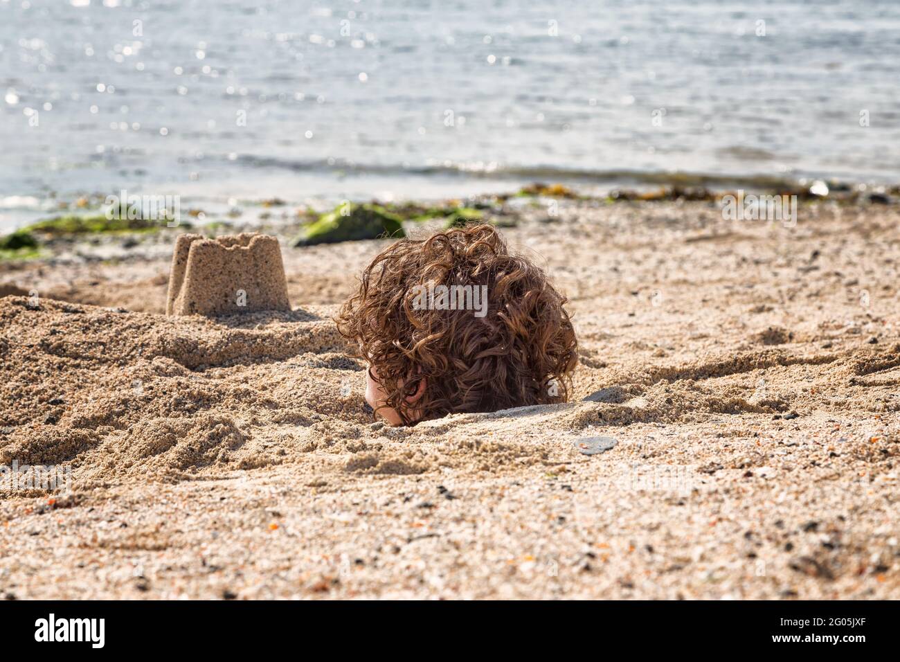 boy with curly hair dug in the sand Stock Photo - Alamy