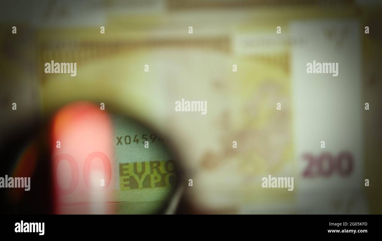 Back side of two hundred euro banknotes examine with magnifying glass ...