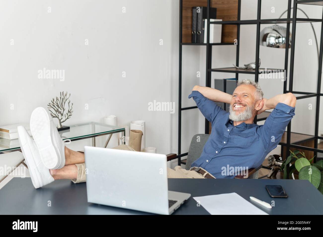 Successful senior man ceo rests on his workplace, contemporary ...