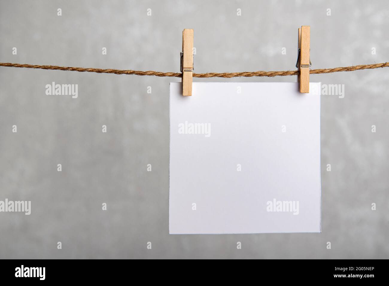 One blank square note paper card hanging with wooden clip or clothespin ...