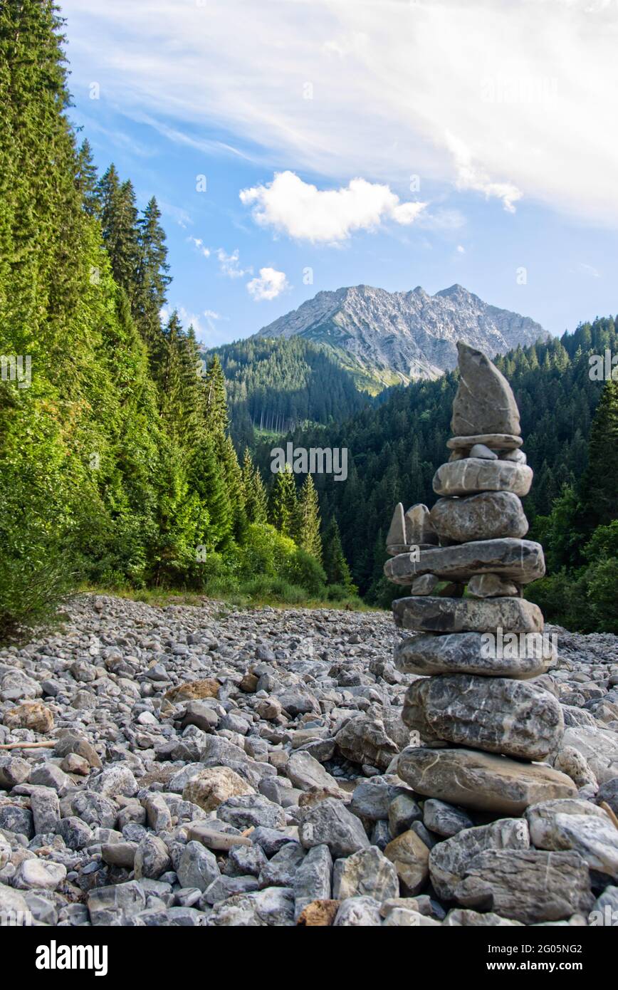 Vertical shot of cairn rocks in the alps under a blue cloudy sky in ...