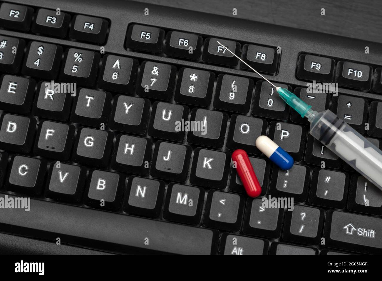 Pills and syringe on computer keyboard. Darknet drug trade concept ...