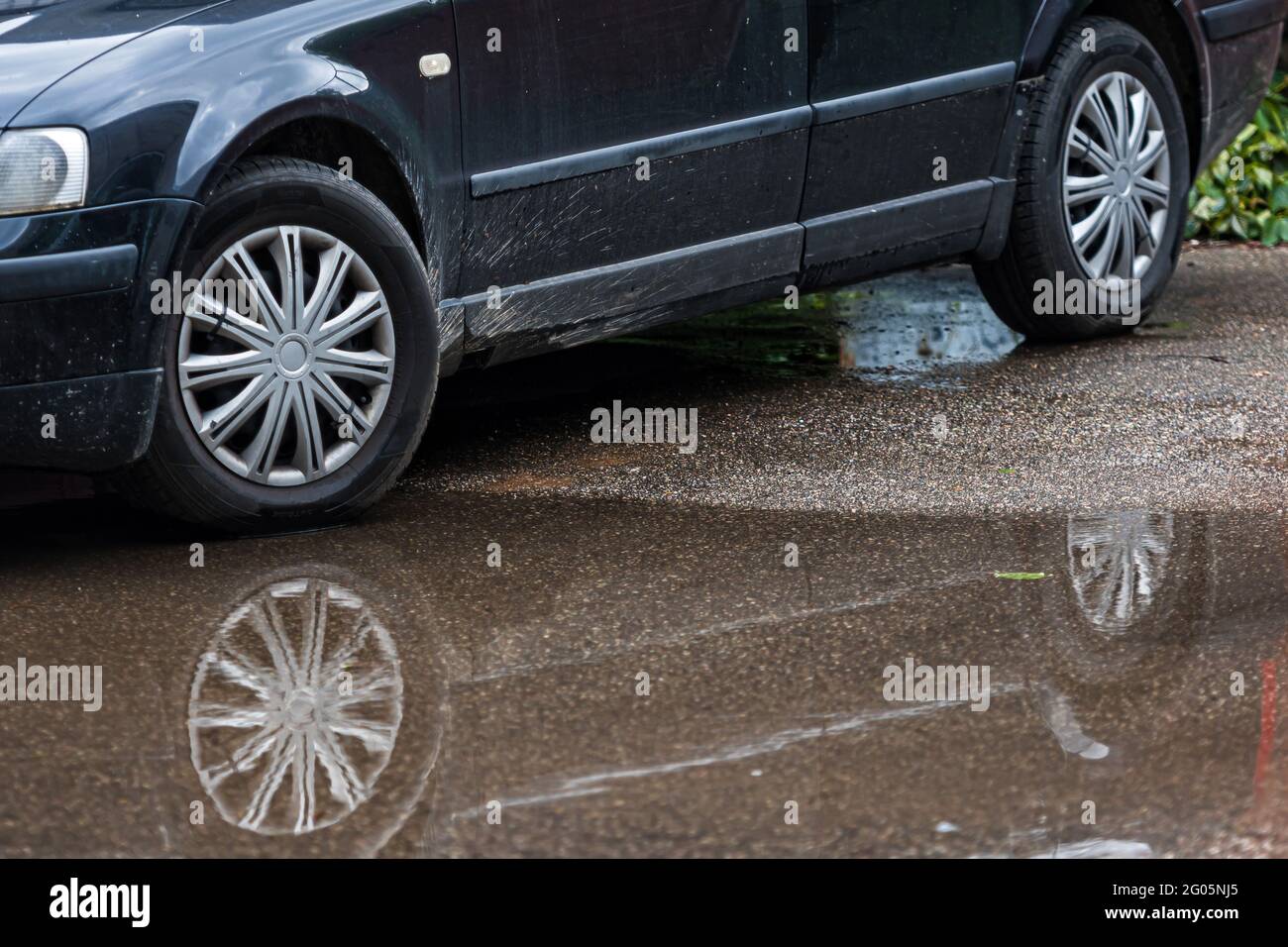 puddle on the sidewalk with a reflection of a parked car, close-up ...