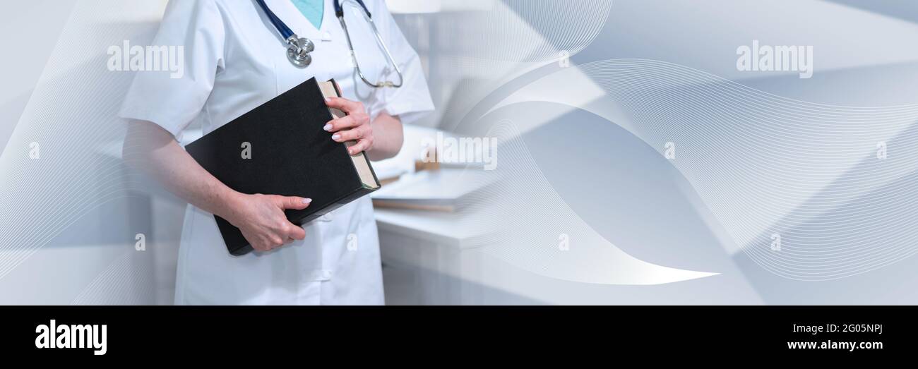 Portrait of female doctor standing and holding a medical textbook ...