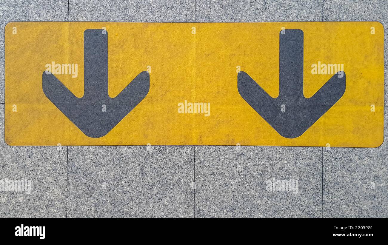 arrow sign in yellow color painted on black on the waiting zone for ...