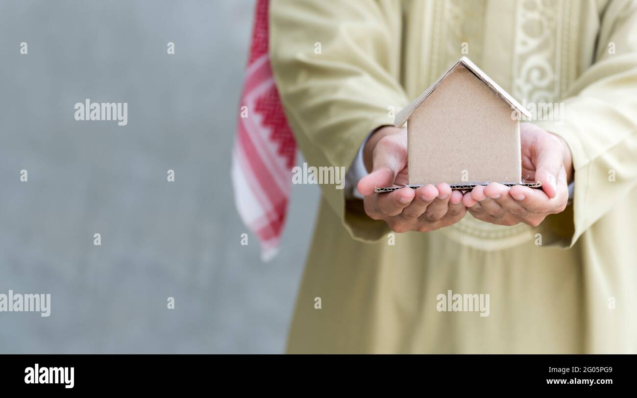 Arab man real estate agent holding house model in hands. Real estate ...