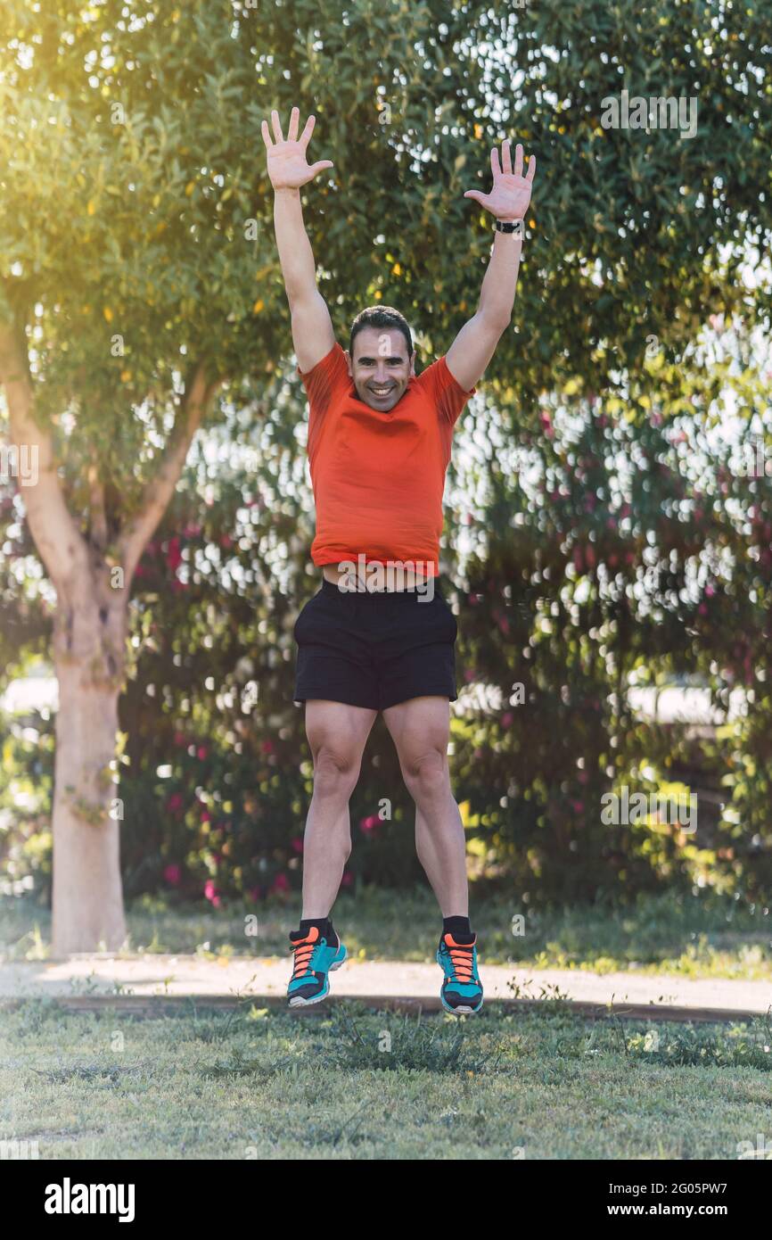 Vertical photo of a man in sports clothes jumping in a park Stock Photo ...