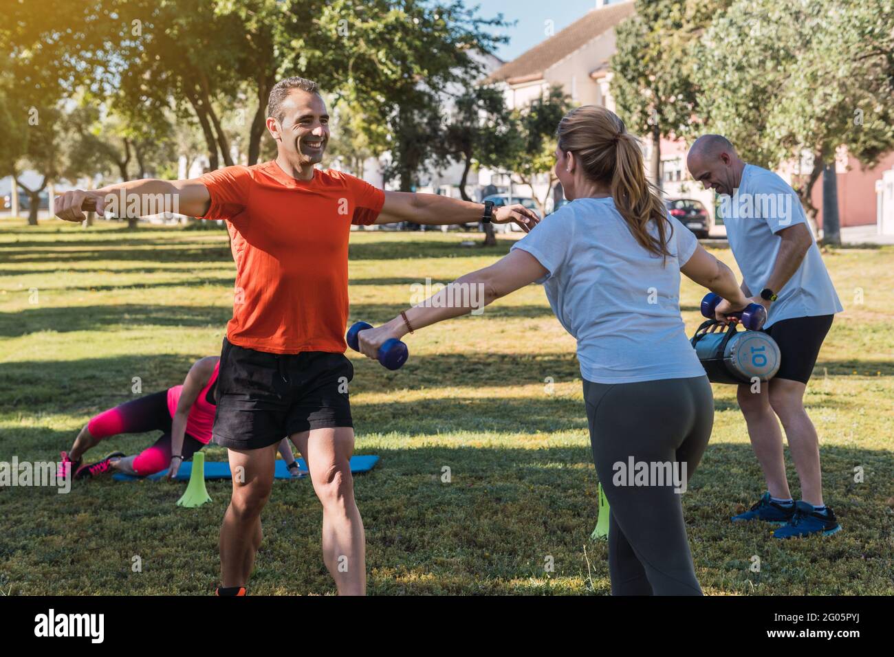 Group of people doing various exercises in a park with a personal ...