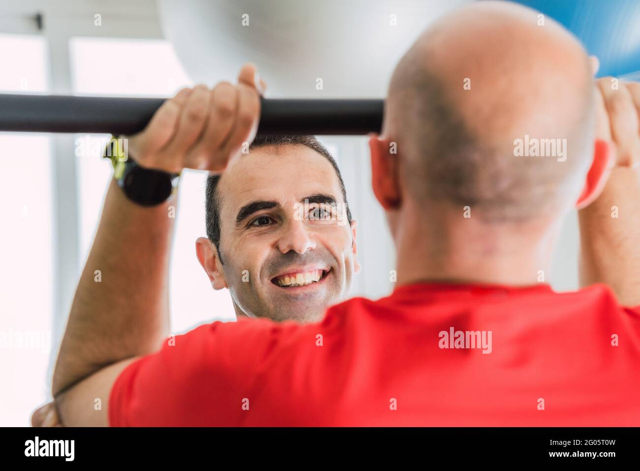 Portrait of a personal trainer smiling in front of a client in a gym ...
