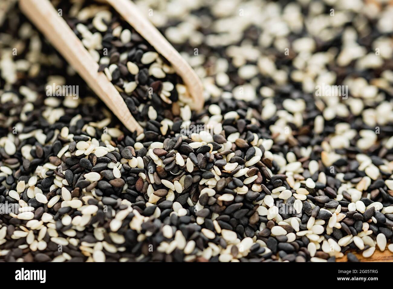 Close up of mix of black and white sesame seed on wooden spoon ...