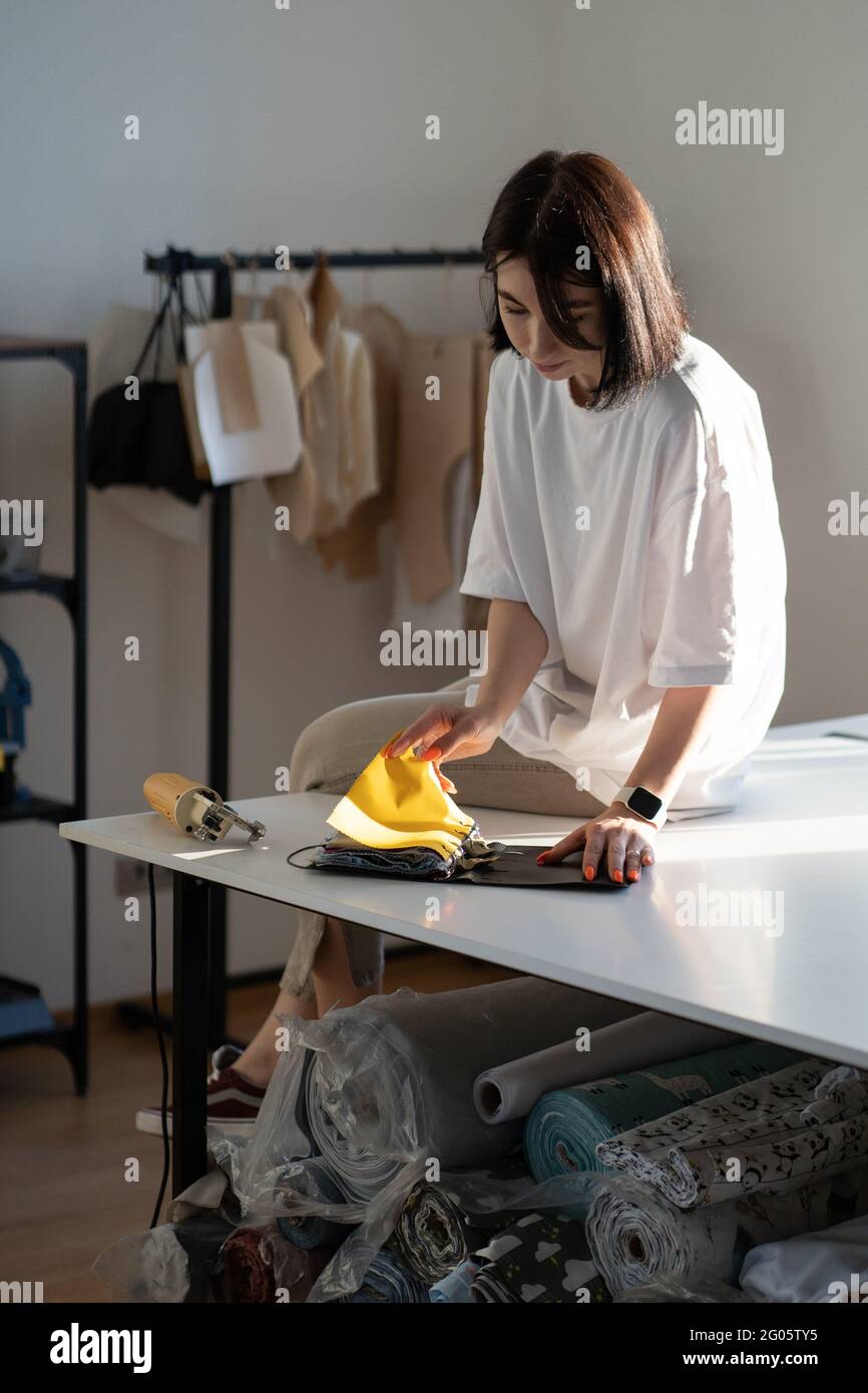 Young designer tailor woman choose swatches of fabric in studio. Girl ...