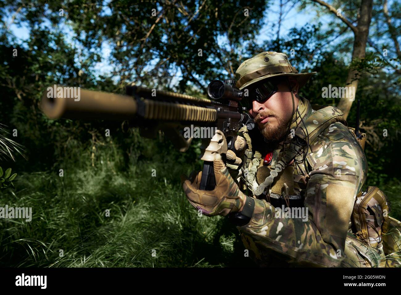 Airsoft player in camouflage uniform aiming at the sight of the weapon ...