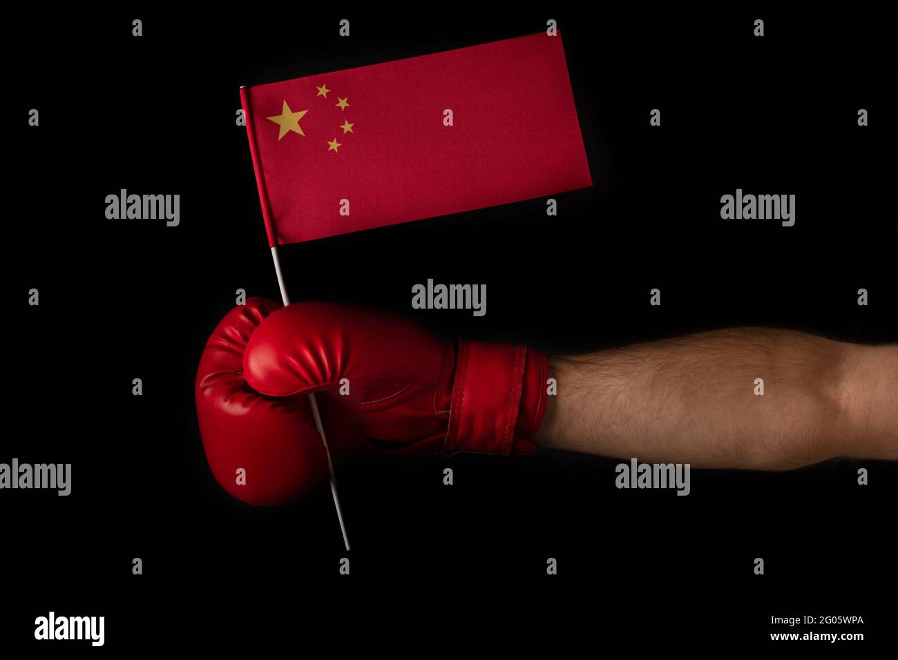 Hand in boxing glove holds the flag of China. Black background Stock ...