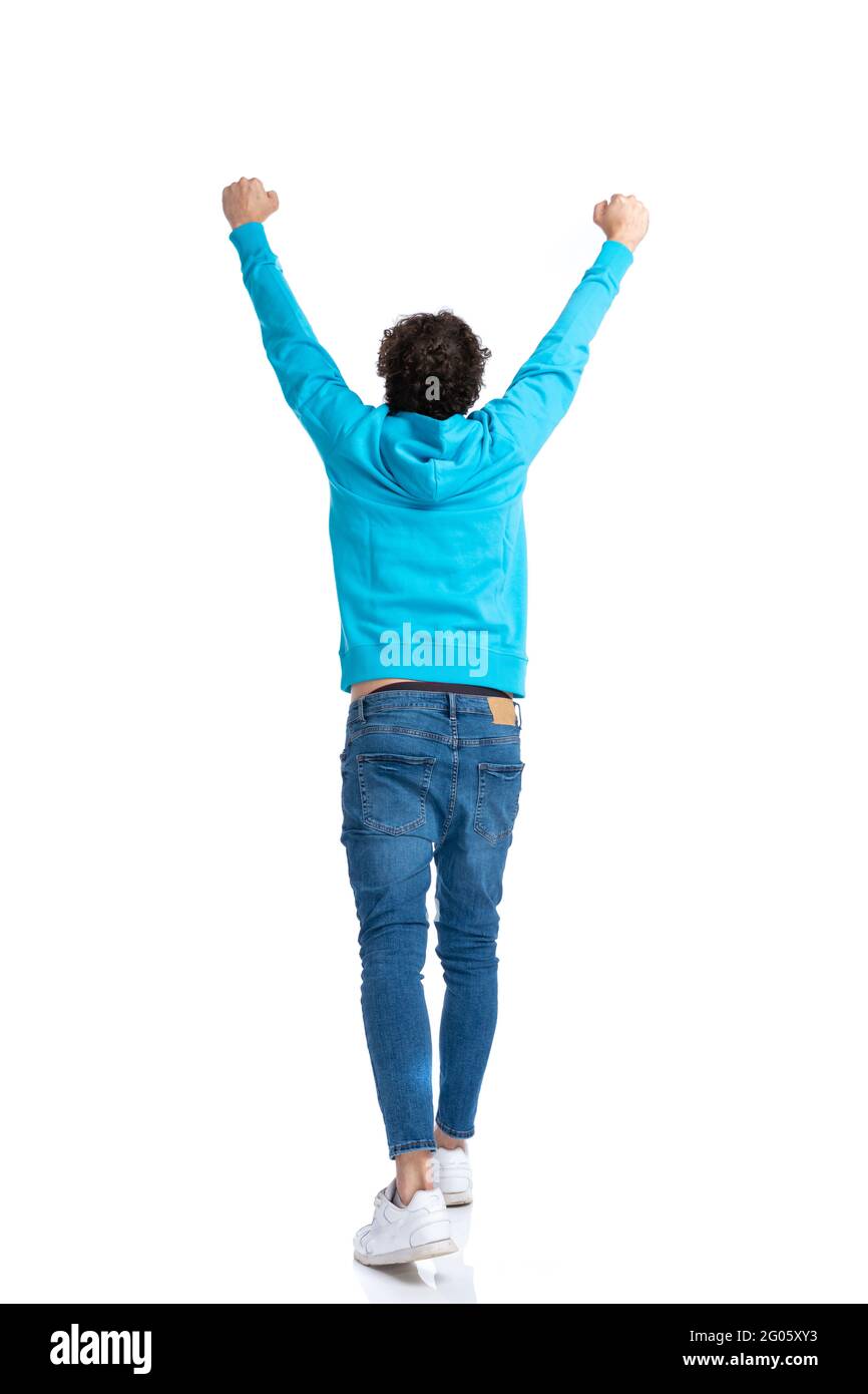 back view of curly casual man in blue hoodie holding arms in the air ...