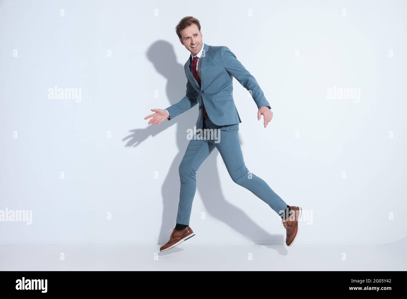 elegant young businessman in blue suit looking to side, leaping up in ...