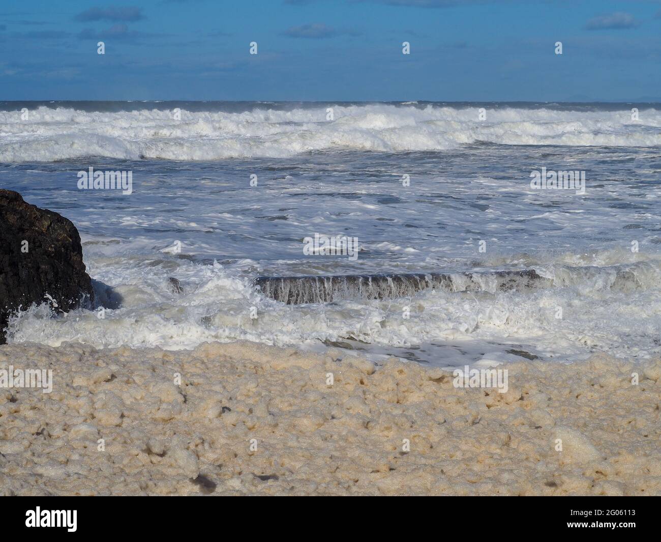 Dirty sea foam blown off the ocean waves crashing into a rock pool by ...