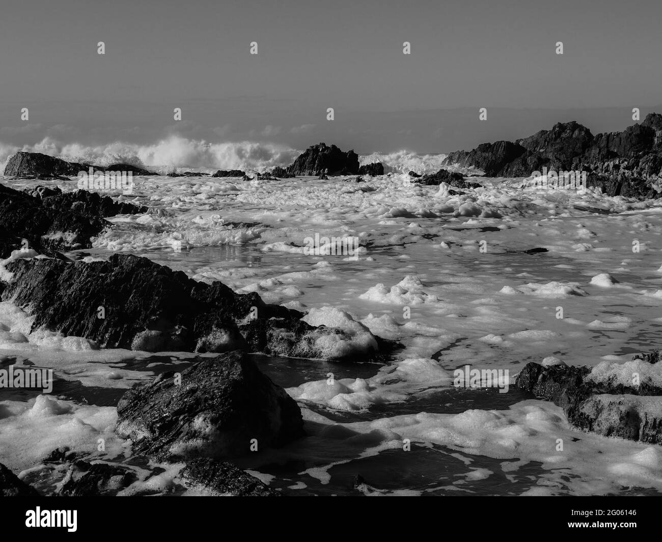 Monochrome of foamy frothy water in the surf as it washes up through ...