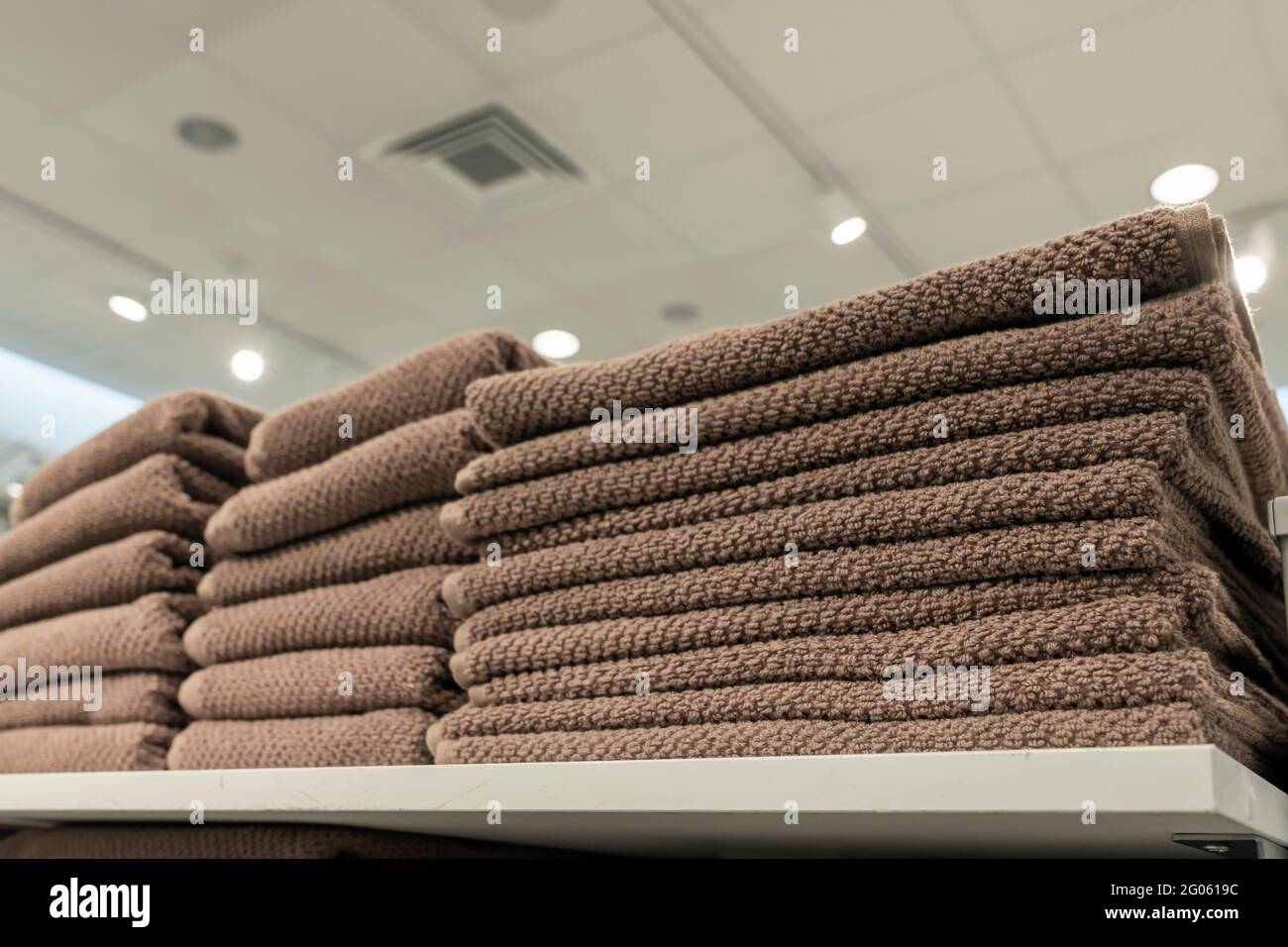 stacks of brown towels on a bed linen store shelf. Sale of home ...