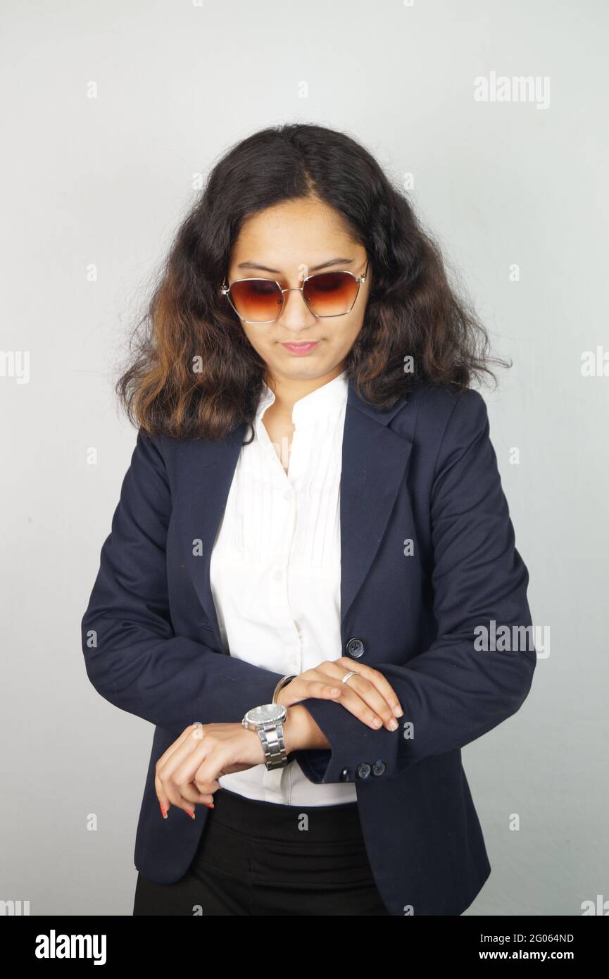 Confident Indian businesswoman with sunglasses looking at her watch ...
