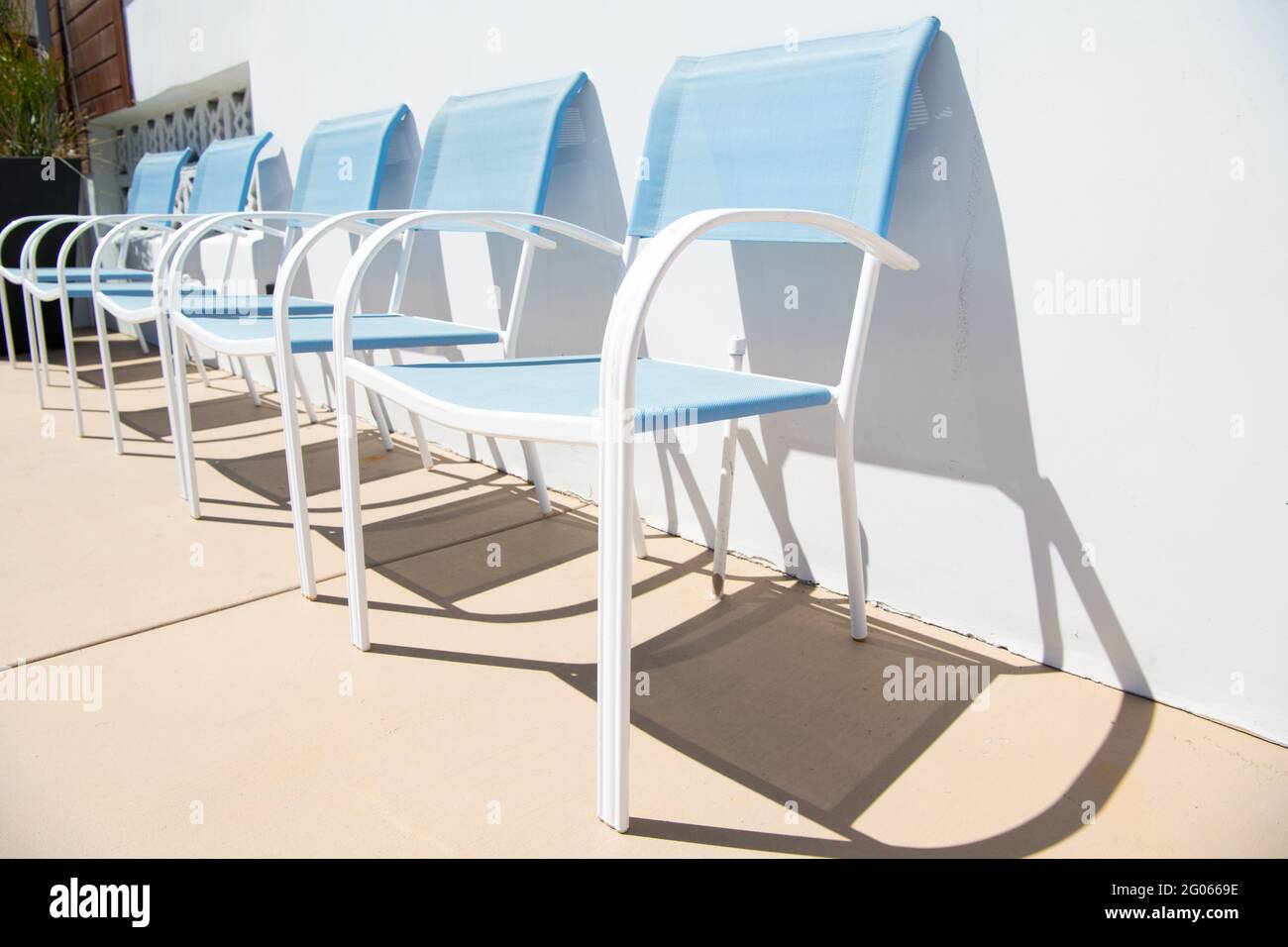Outdoor lounge chairs. Blue patio chairs at sunny wall. Patio or ...