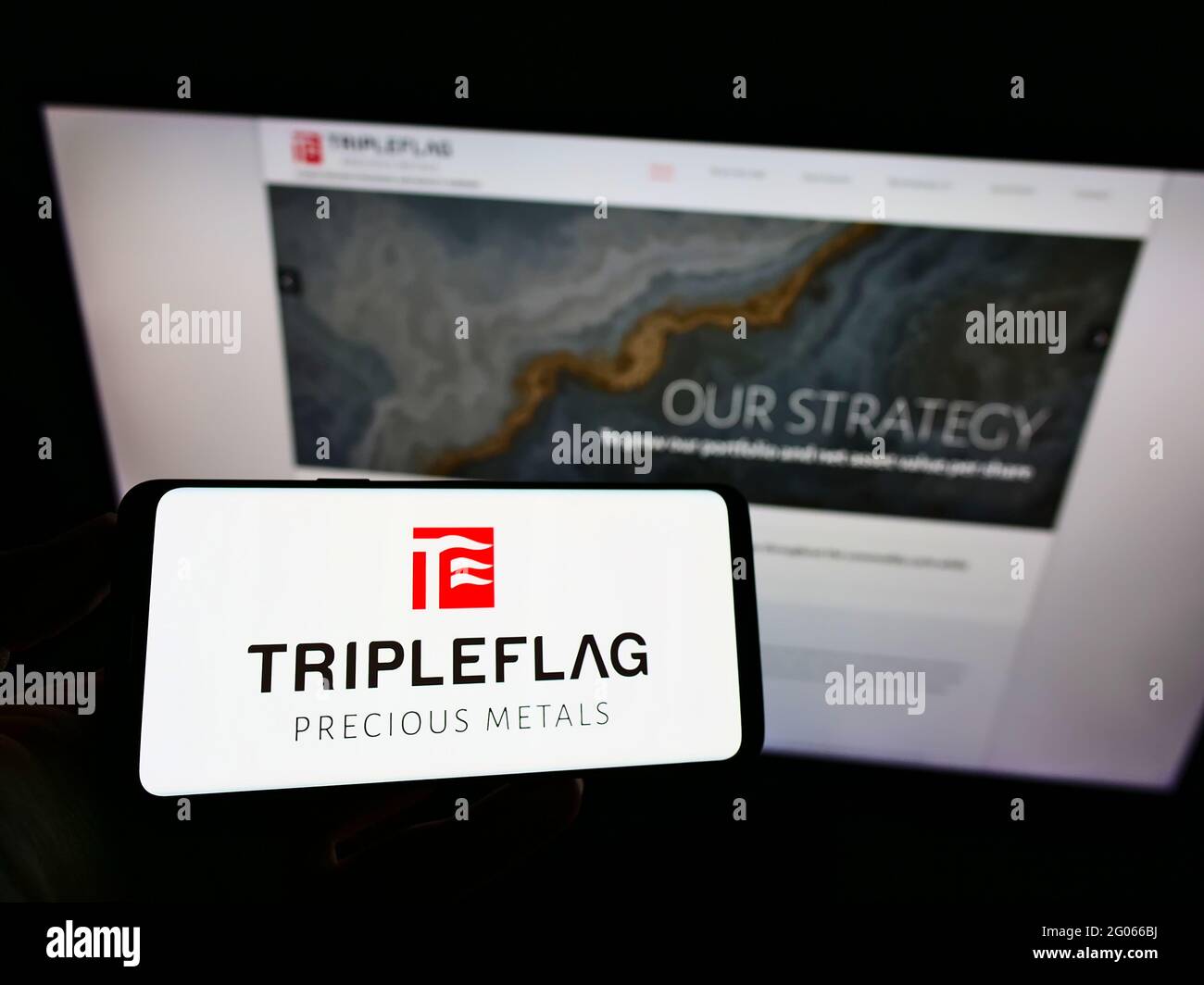 Person holding mobile phone with logo of Canadian company Triple Flag ...