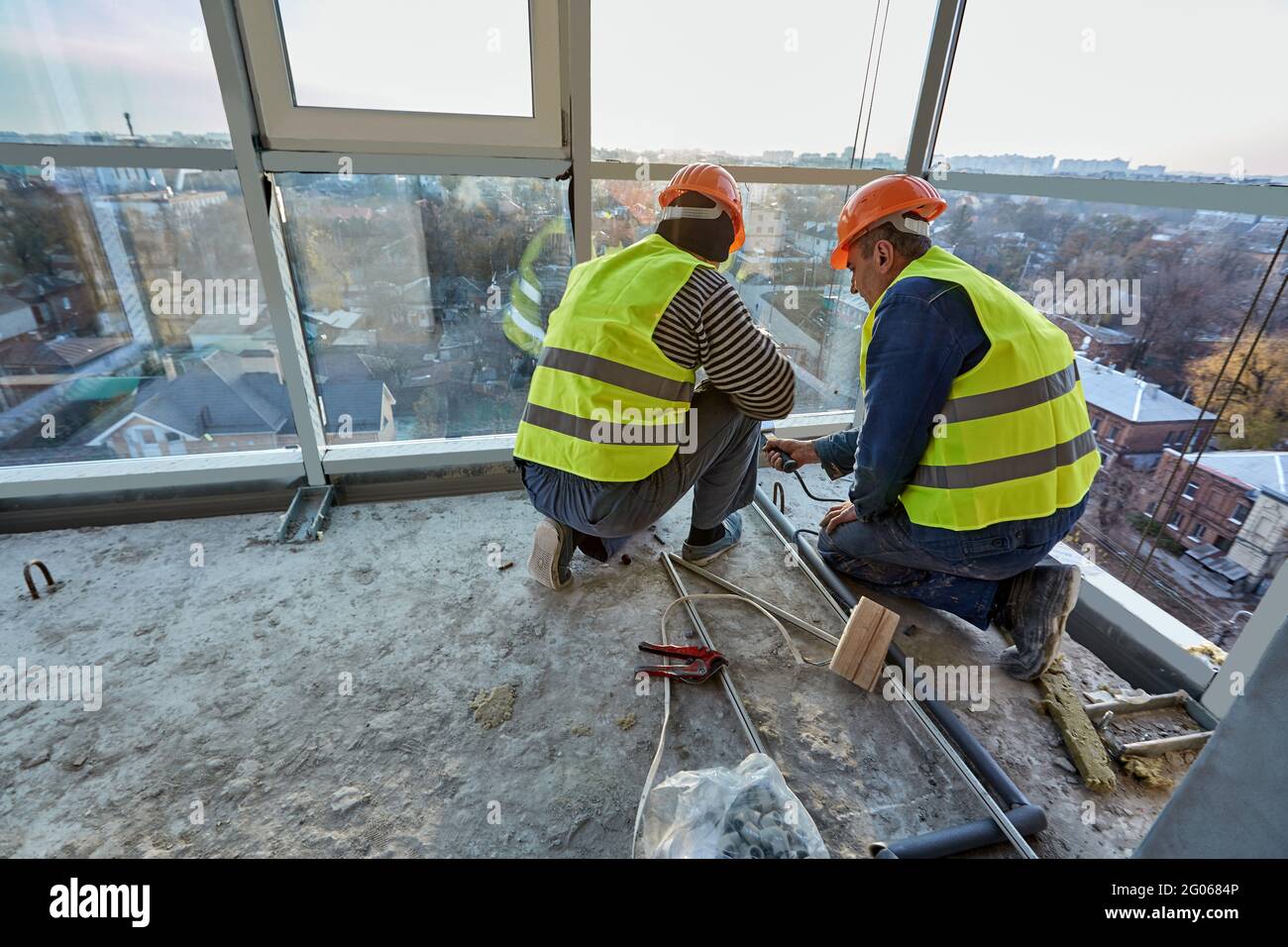 Two workers in protective clothing and safety helmets installing ...