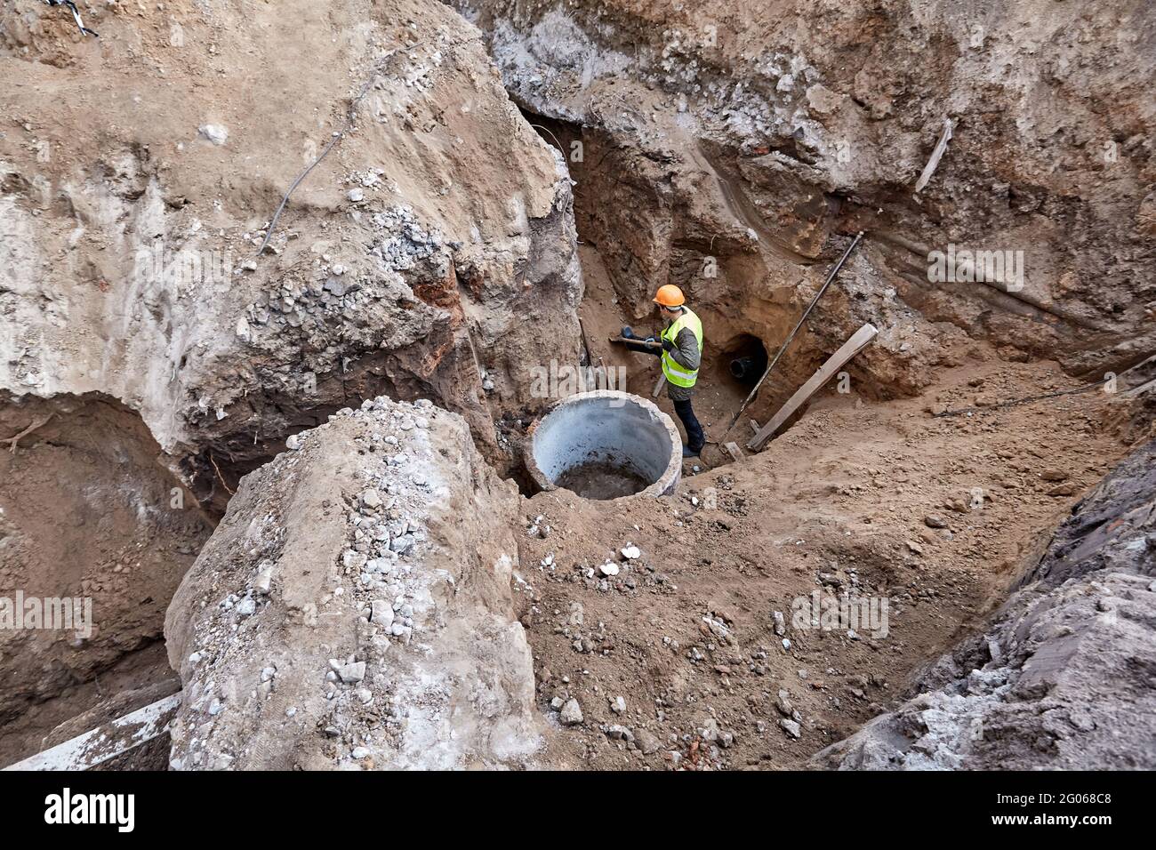 Worker is digging out a trench with a shovel in an excavation pit to ...