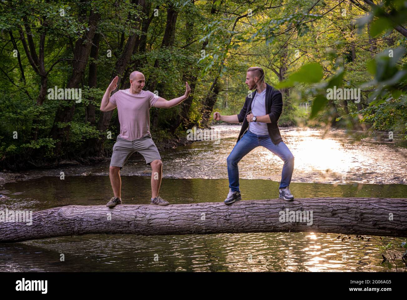 Two guys play fighting in martial arts style on a log bridge Stock ...
