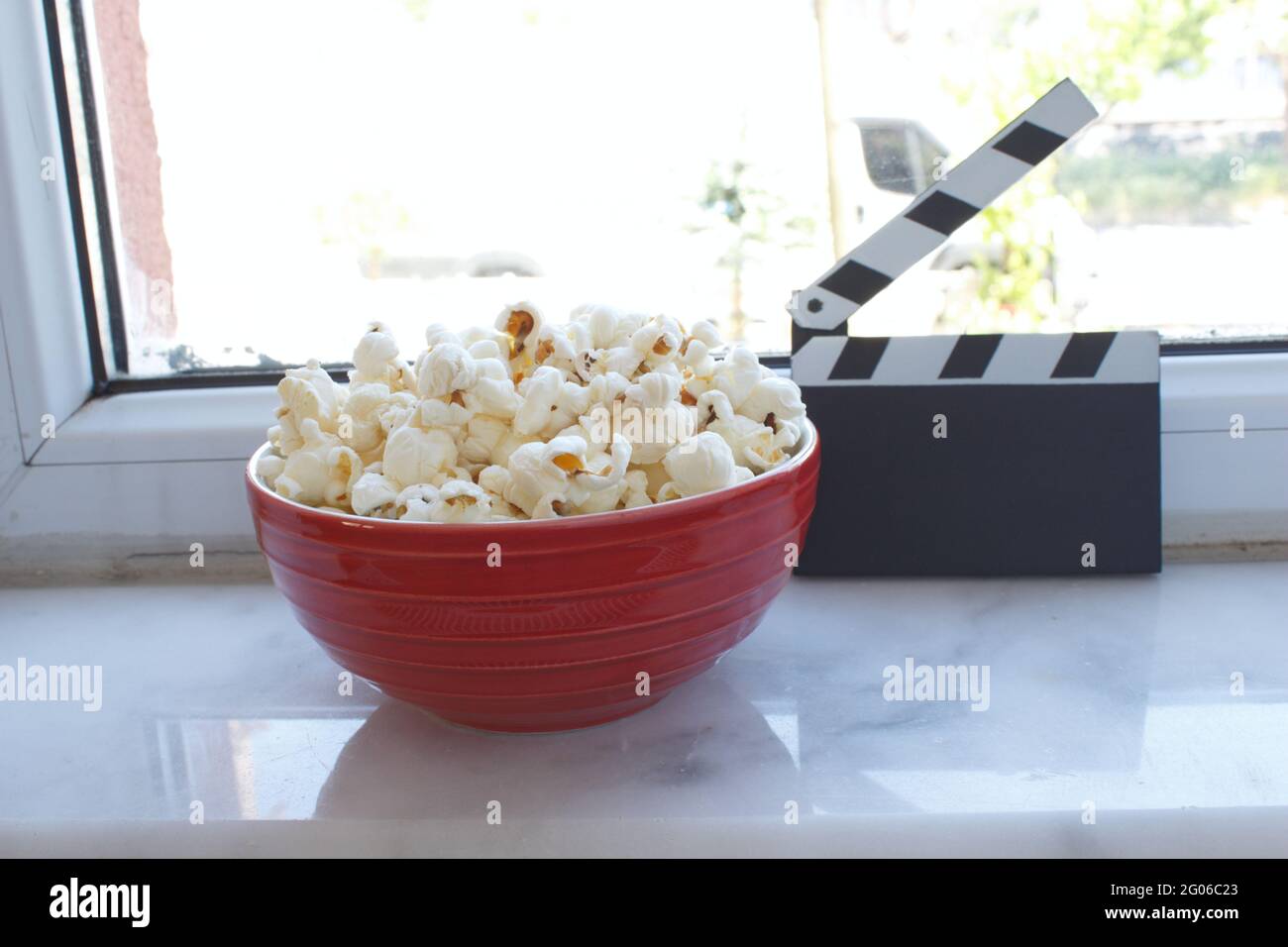 Close-up bowl of popcorn and movie clapperboard. Salty and fatty ...