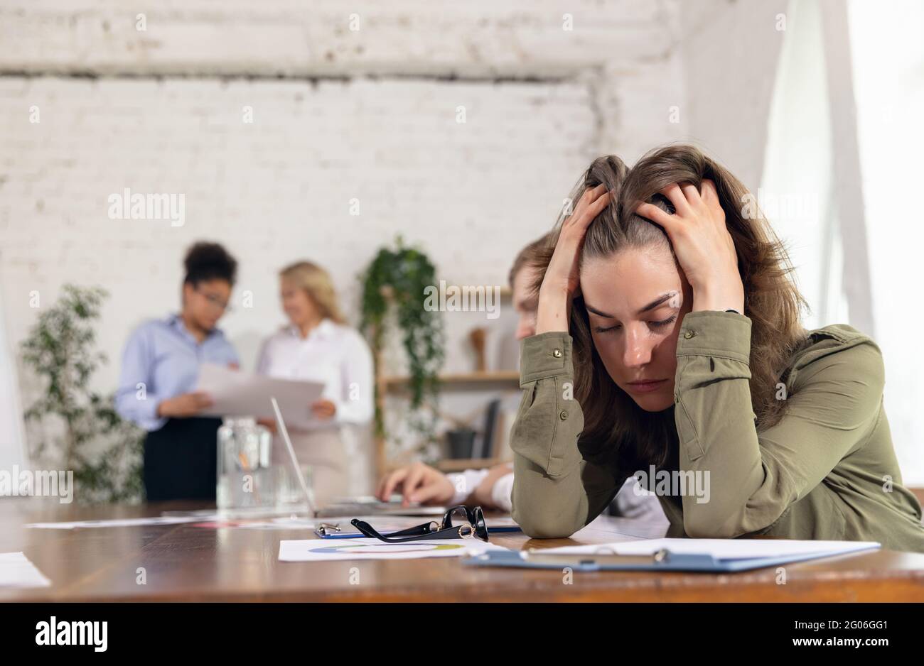 Young tired woman at modern office with colleagues. Concept of ...