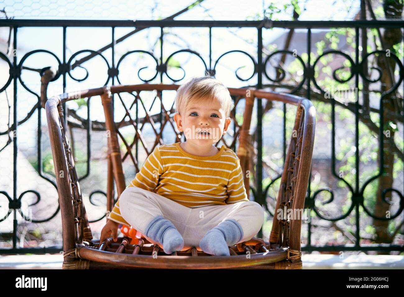 Kid sits on a wicker chair on the balcony against the background of a ...