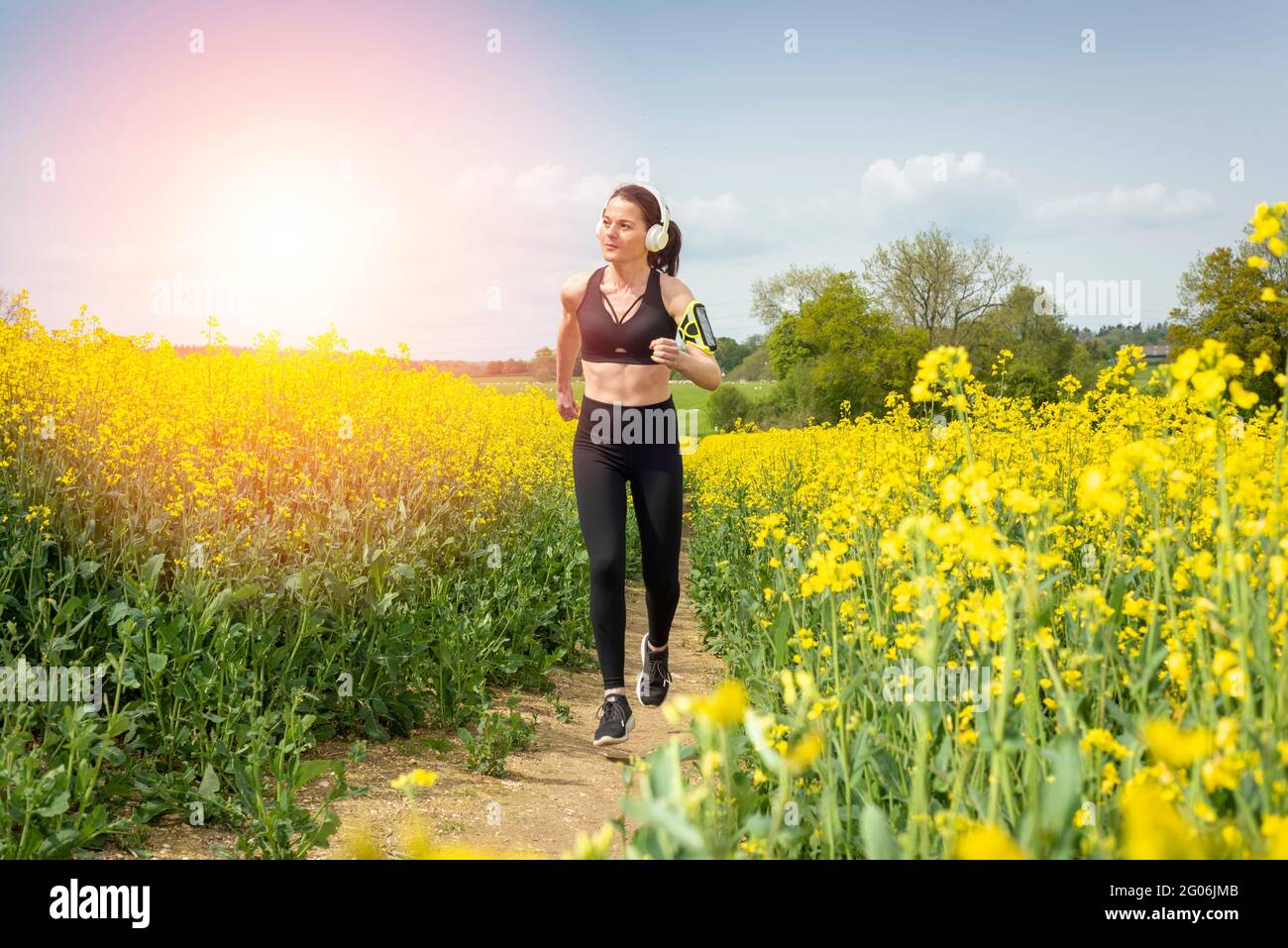 Woman jogging through a yellow rapeseed field in the countryside ...
