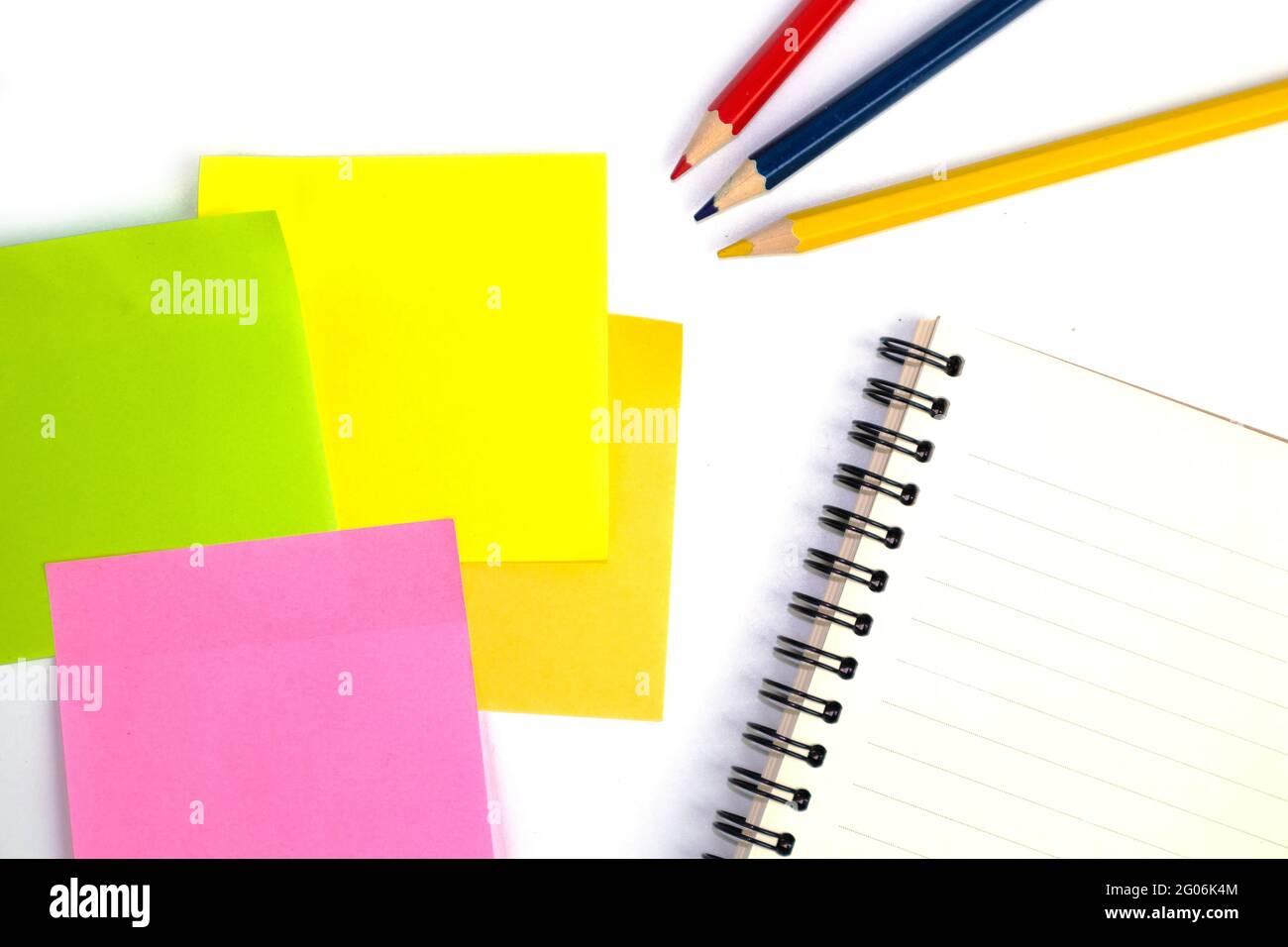 color pencils and notebooks and sticky note placed on a white ...