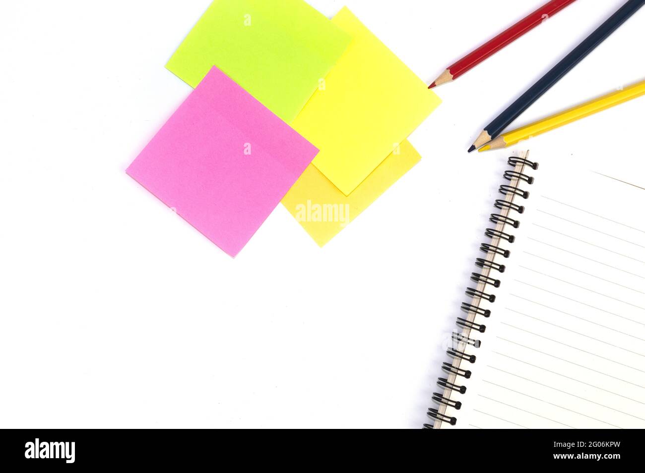 color pencils and notebooks and sticky note placed on a white ...