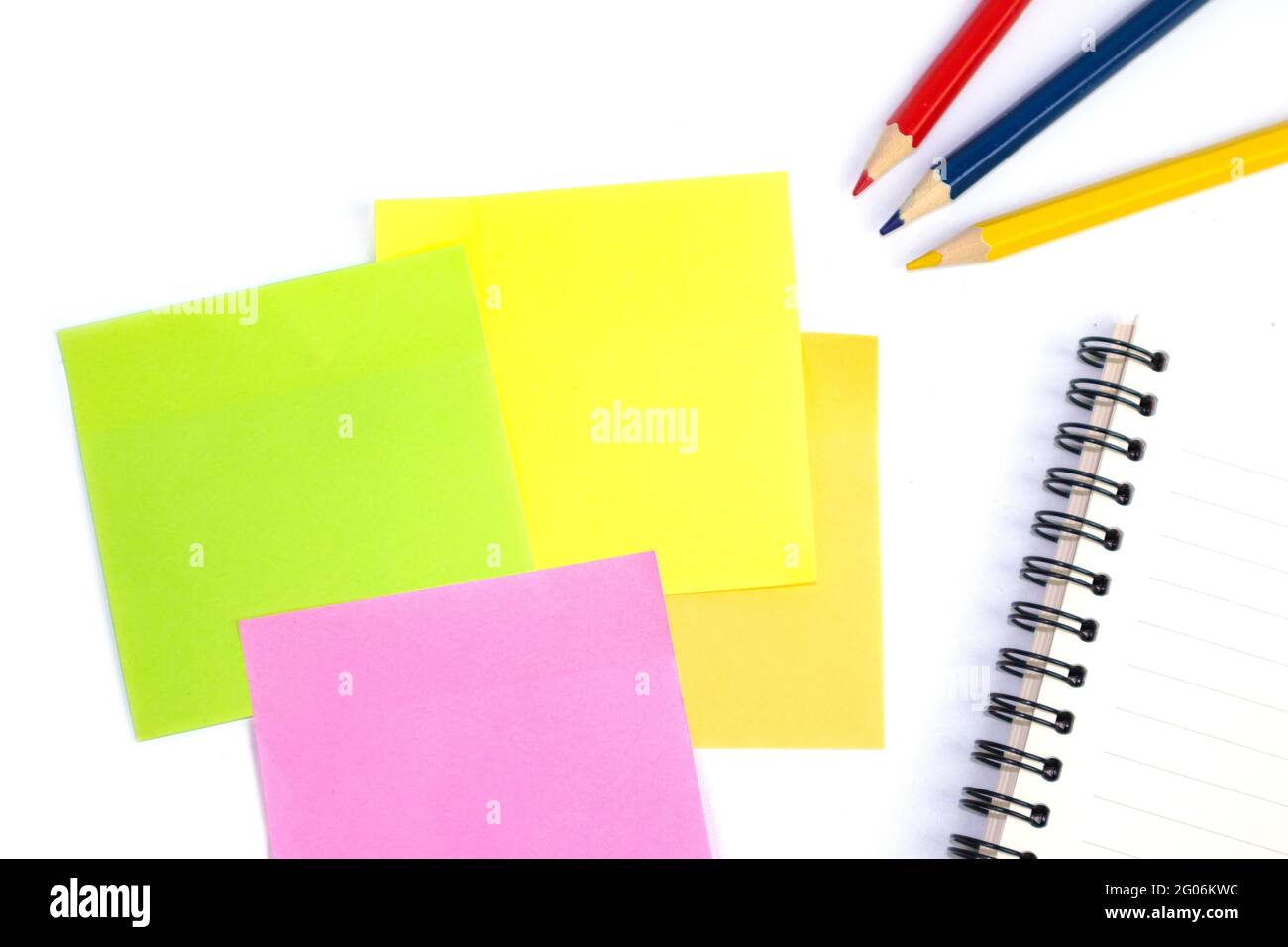color pencils and notebooks and sticky note placed on a white ...