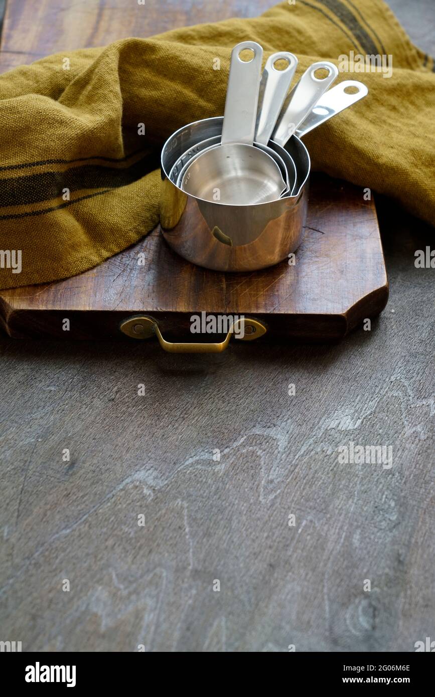 Small steel measuring bowls on wooden cutting board and tea towel ...
