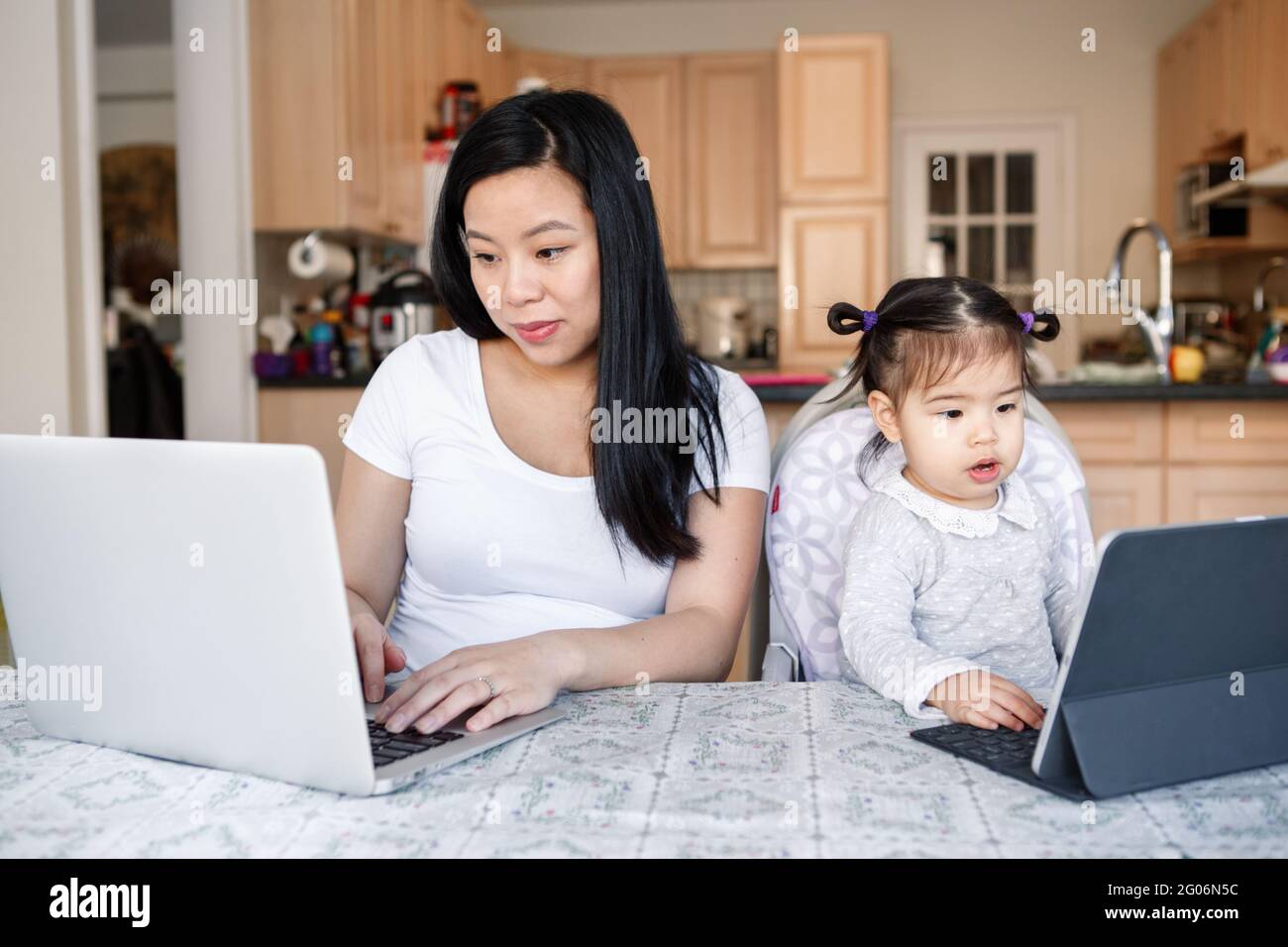 Asian Chinese mother with daughter baby working together on laptop ...