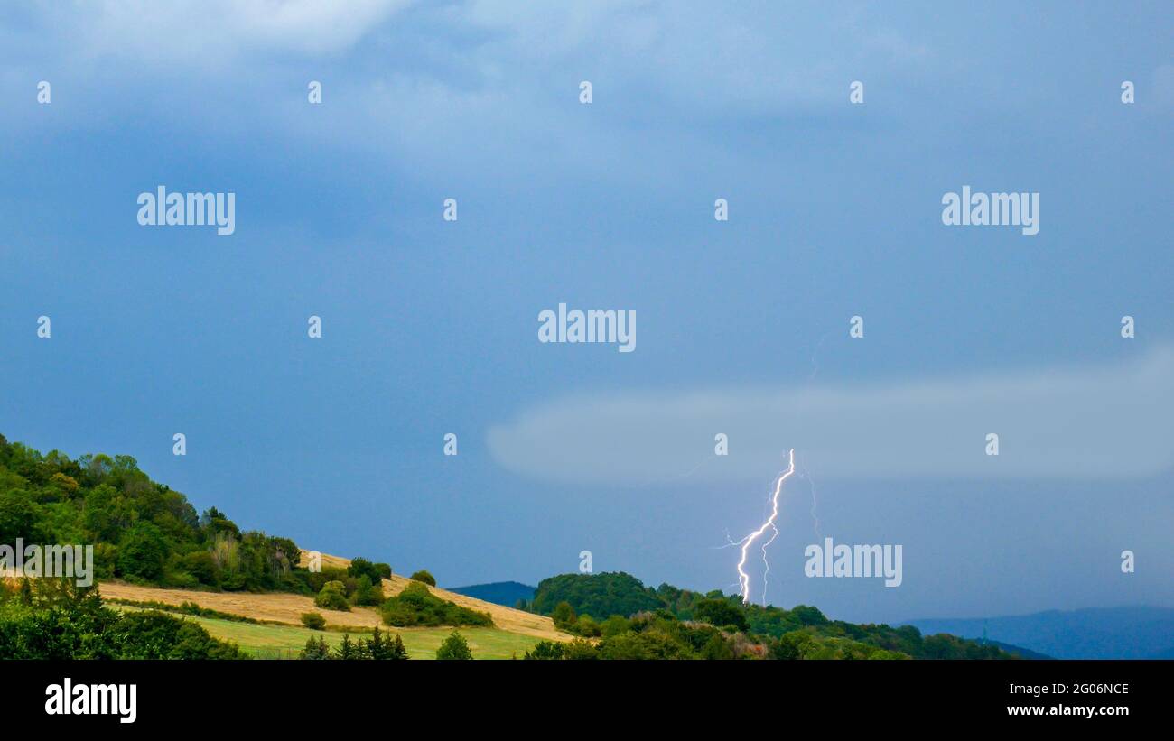 Storm with lightning over the hilly landscape. Lightning strikes ...