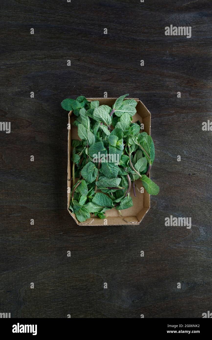 Fresh mint leaves in a cardboard box on wooden background, copy space ...