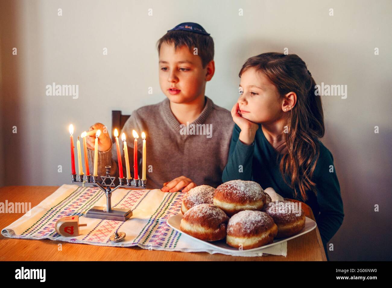 Brother and sister siblings lighting candles on menorah for Jewish ...