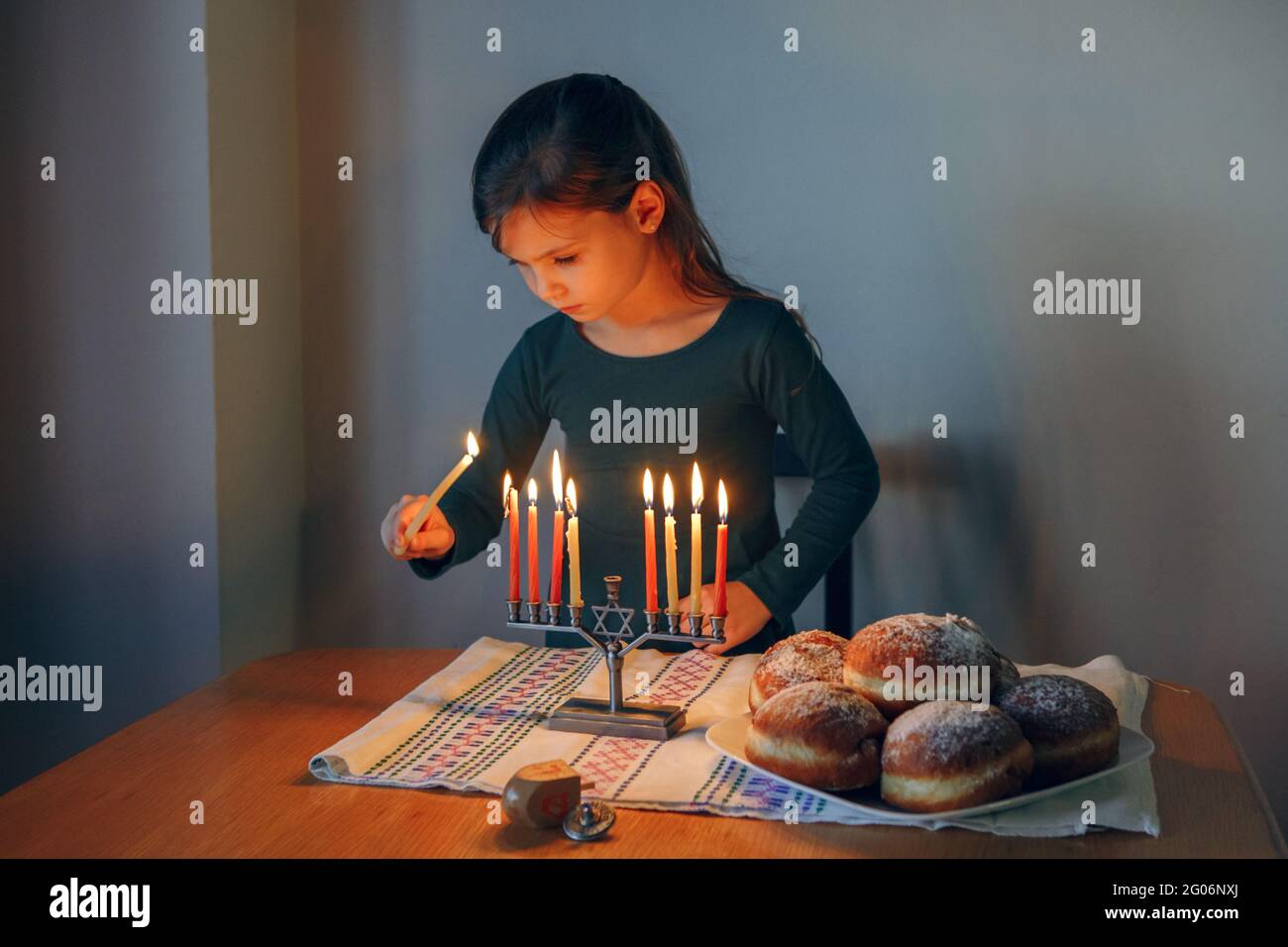 Traditional winter Jewish Hanukkah holiday. Girl lighting candles on ...