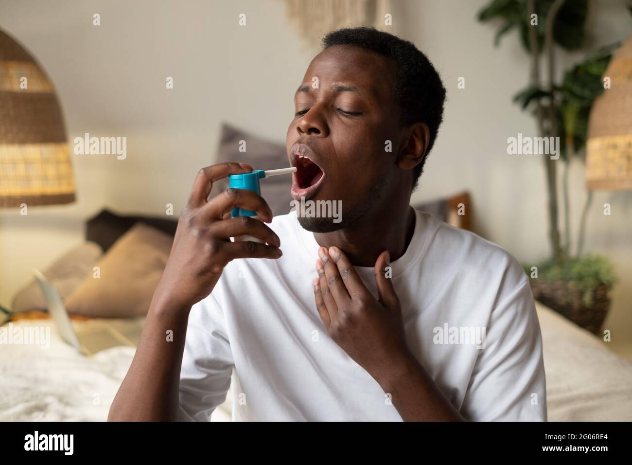 Young african man using asthma inhaler sitting at home Stock Photo - Alamy
