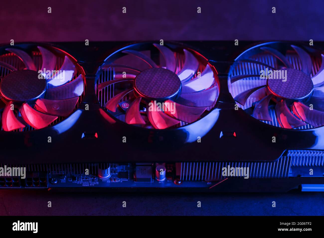 A graphics card with a row of fans with a cyanotic purple backlight in ...