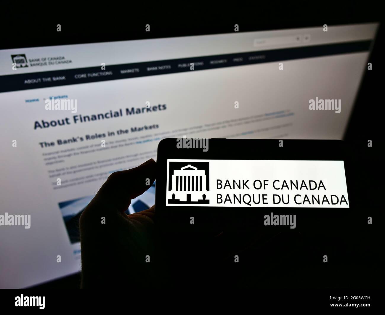 Person holding mobile phone with logo of Crown corporation Bank of ...