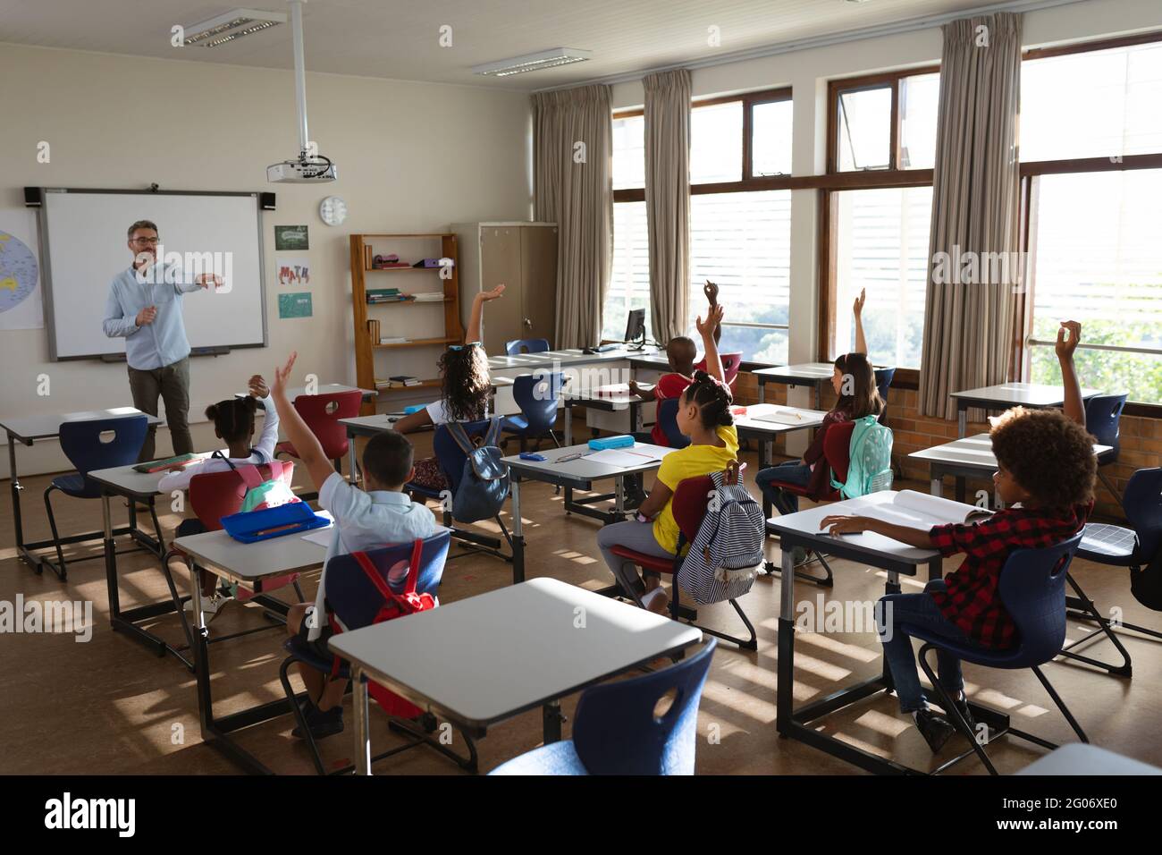 Group of diverse students raising their hands in the class at ...