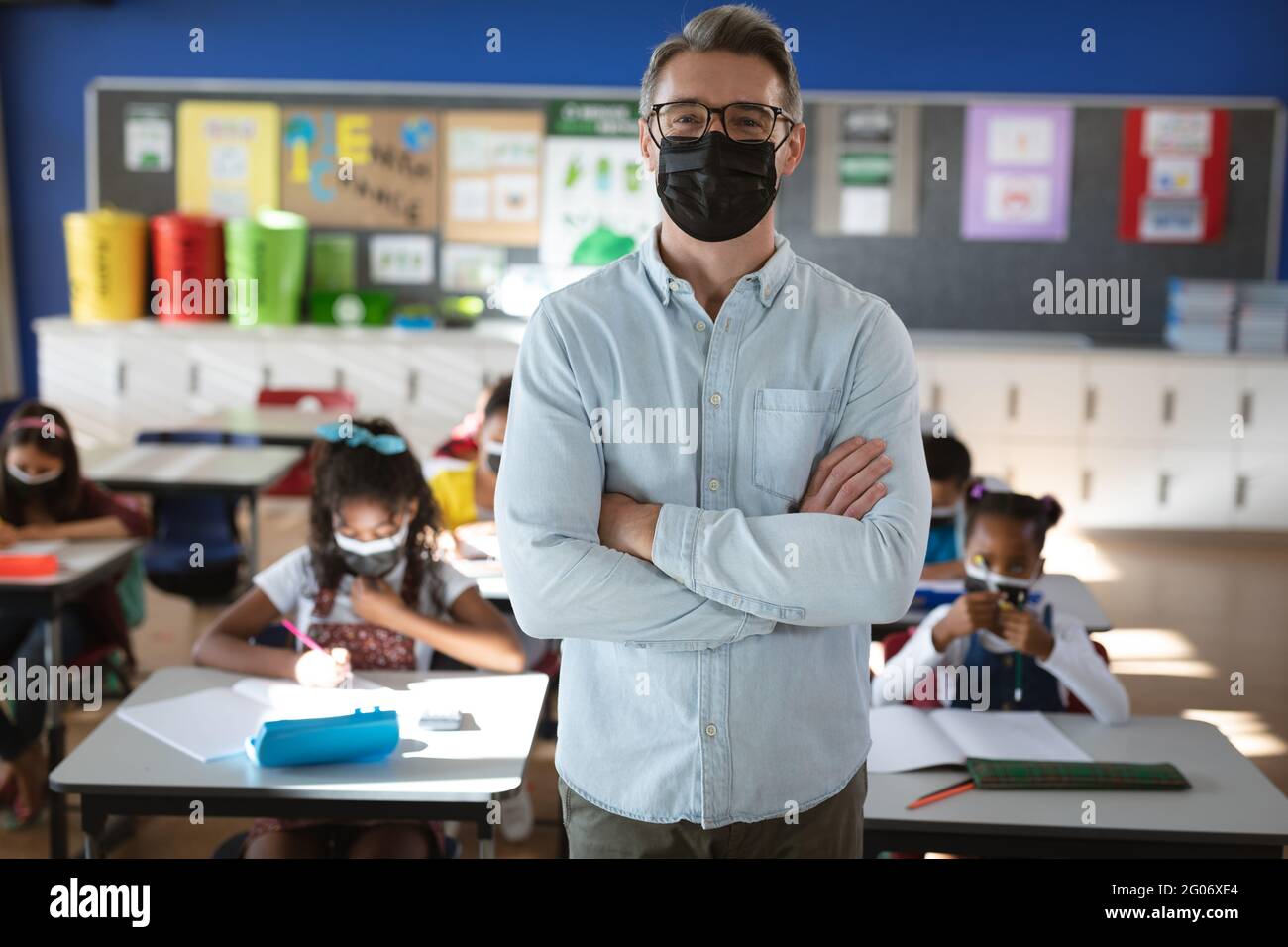 Portrait of caucasian male teacher wearing face mask standing in the ...