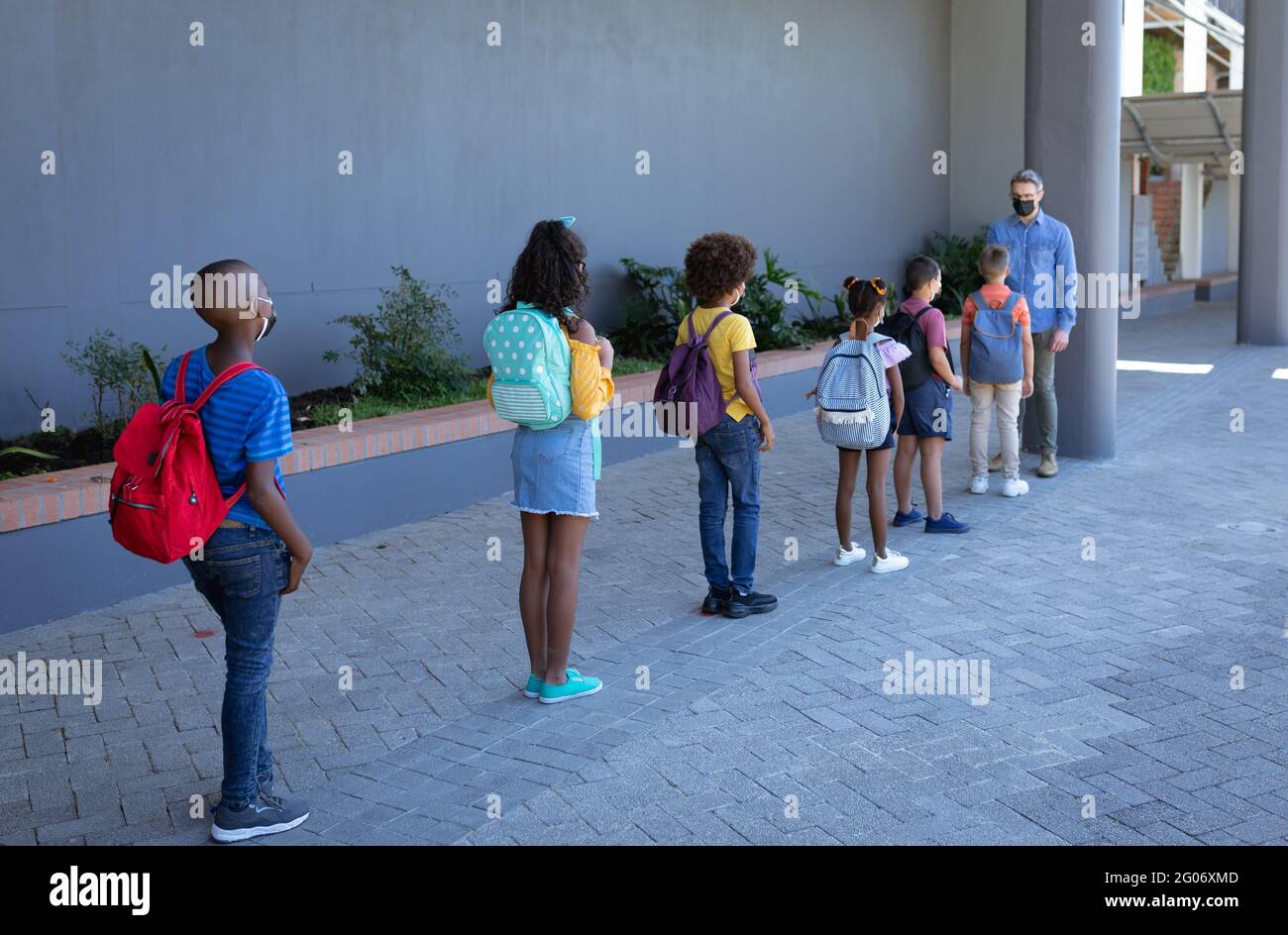 Caucasian male teacher measuring temperature of group of students ...