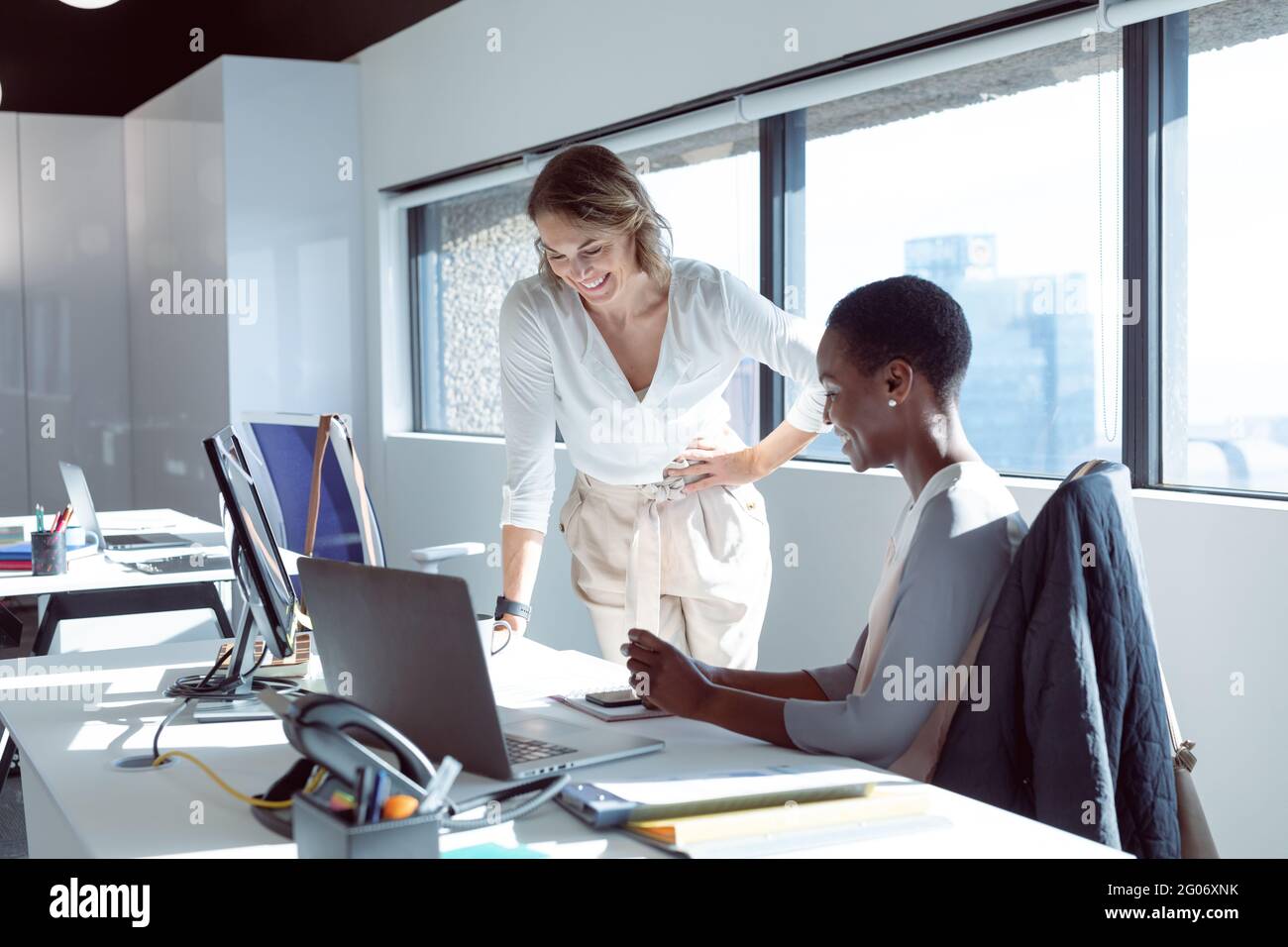 Two diverse smiling businesswomen working together, using laptop ...