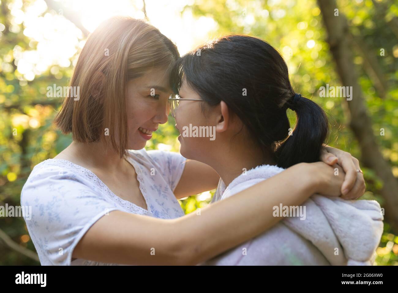 Portrait of smiling asian woman with her daughter touching heads and ...